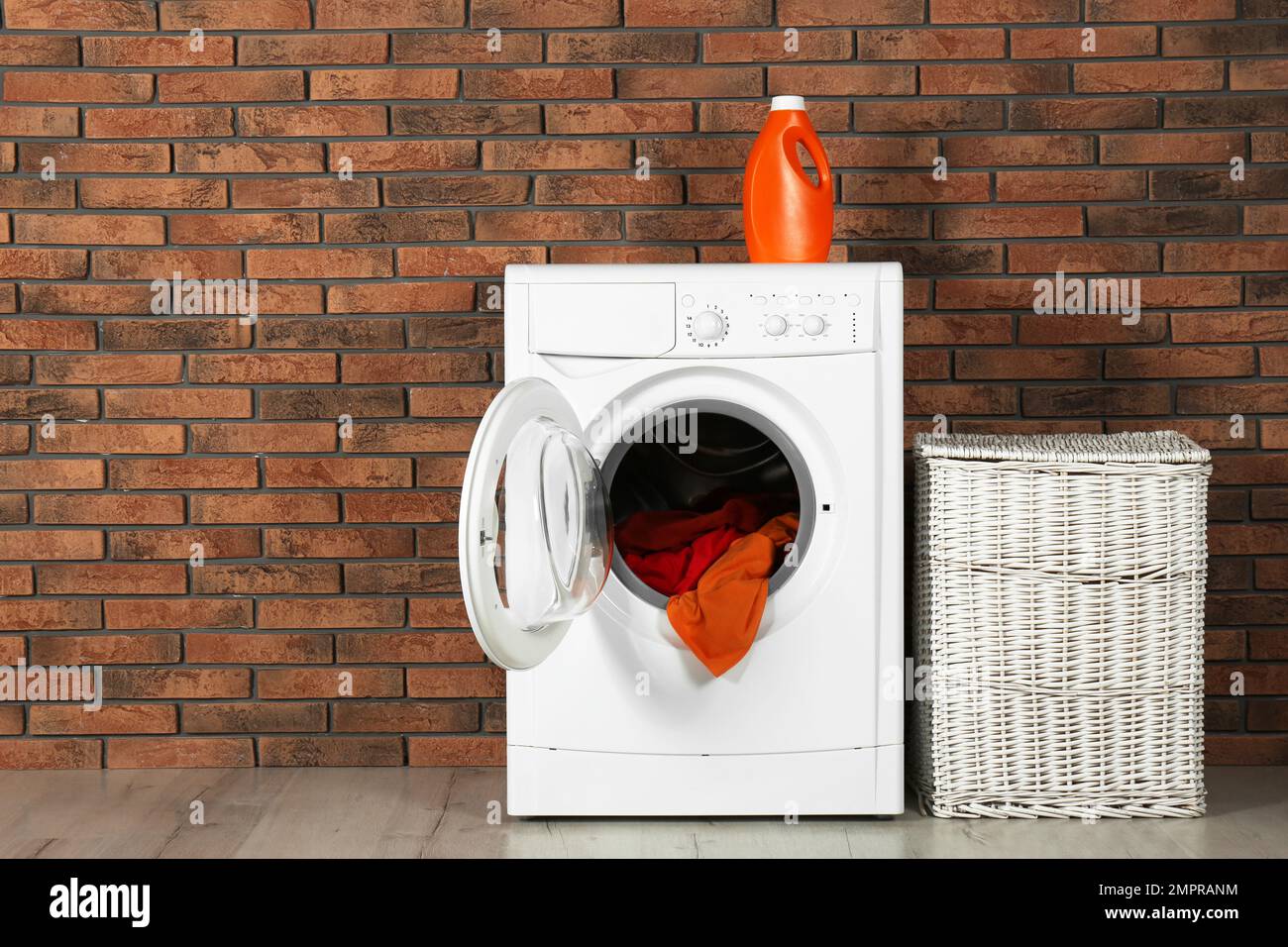 Modern washing machine with laundry, detergent and wicker basket near ...