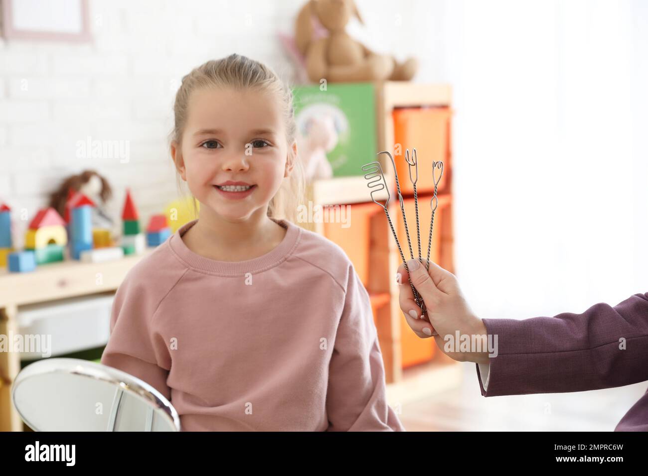 Speech therapist using logopedic probes on session with little girl in ...
