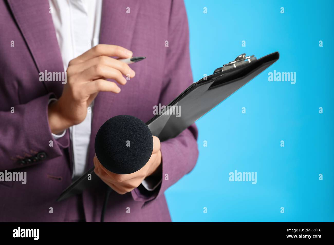 Professional journalist taking notes on light blue background, closeup ...