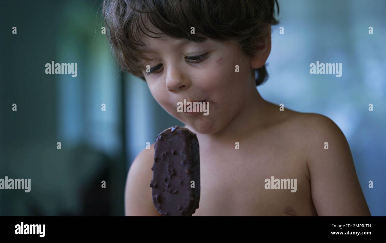 Young boy taking a bite of ice cream. Small child eats unhealthy ...