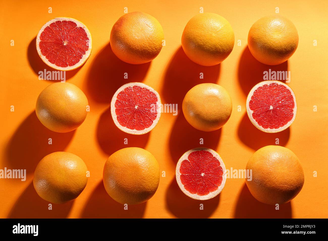 Cut and whole ripe grapefruits on orange background, flat lay Stock ...