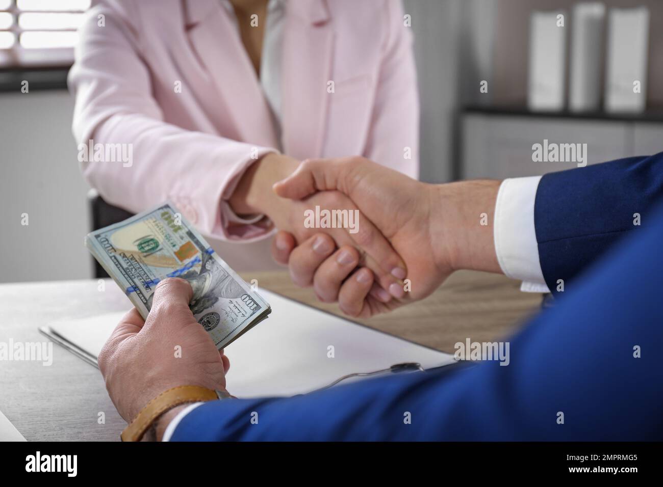 Man shaking hands with woman and offering bribe at table, closeup Stock ...
