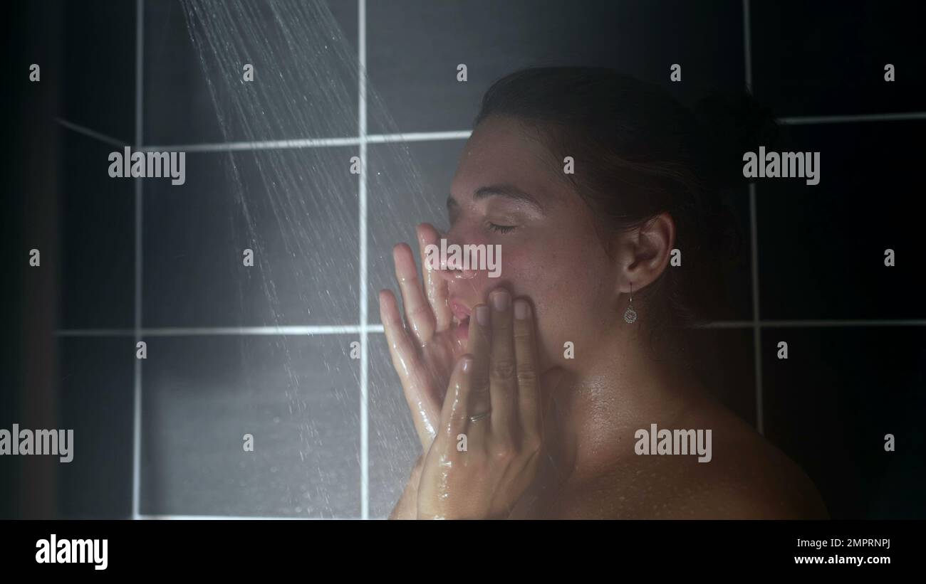 Woman showering face and body relaxing in shower bath. Person washing ...
