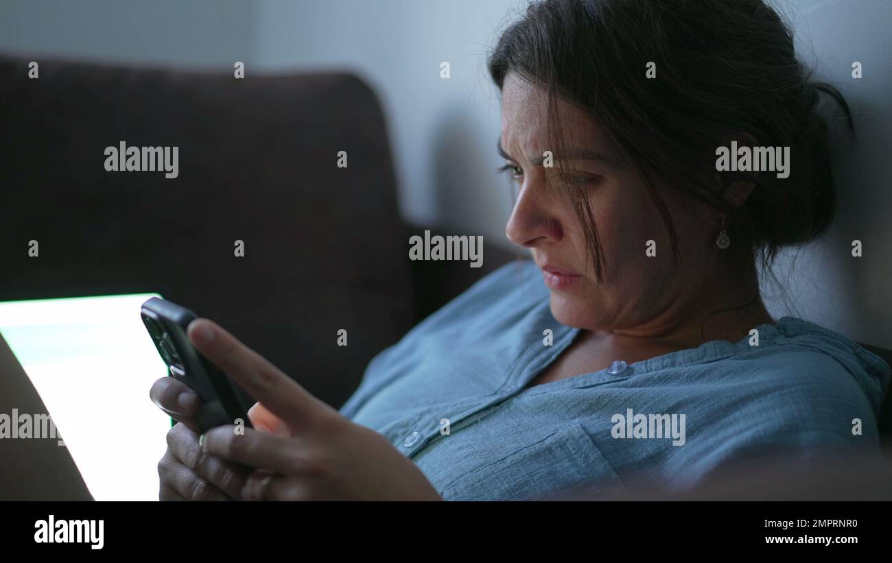 Worried woman looking at cellphone device with concerned emotion ...