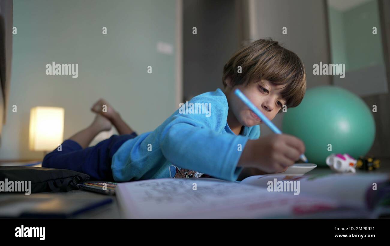 One Concentrated child doing school homework activity in bedroom ...