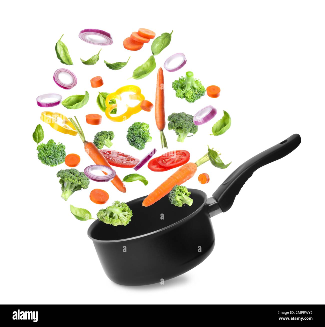 Many different ingredients falling into saucepan on white background ...