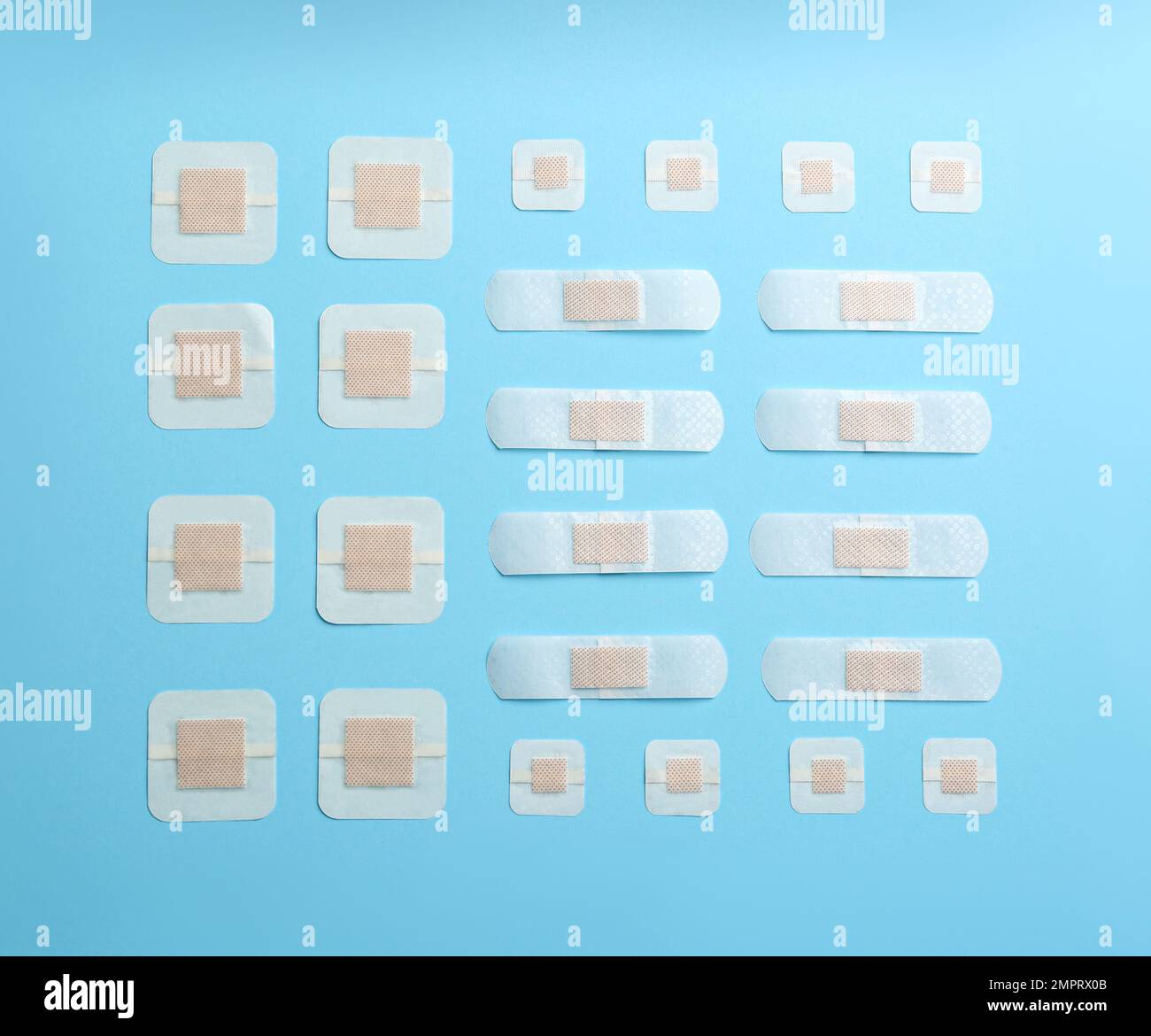 Different types of sticking plasters on light blue background, flat lay ...