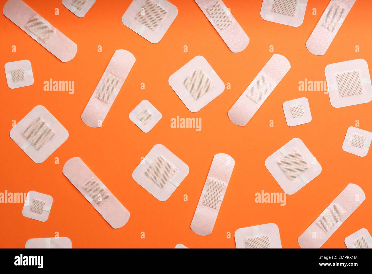 Different types of sticking plasters on orange background, flat lay ...