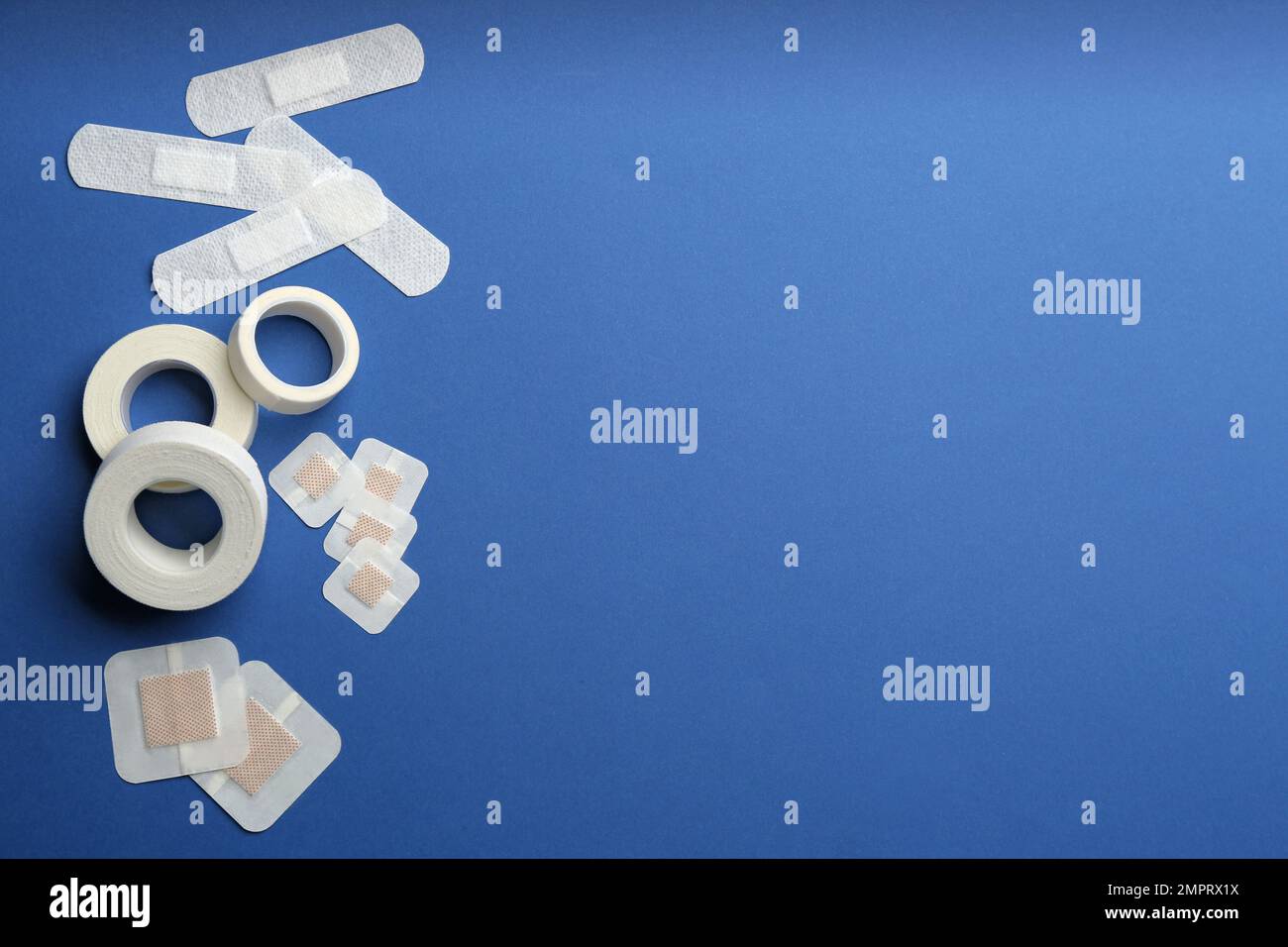 Different types of sticking plasters on blue background, flat lay ...