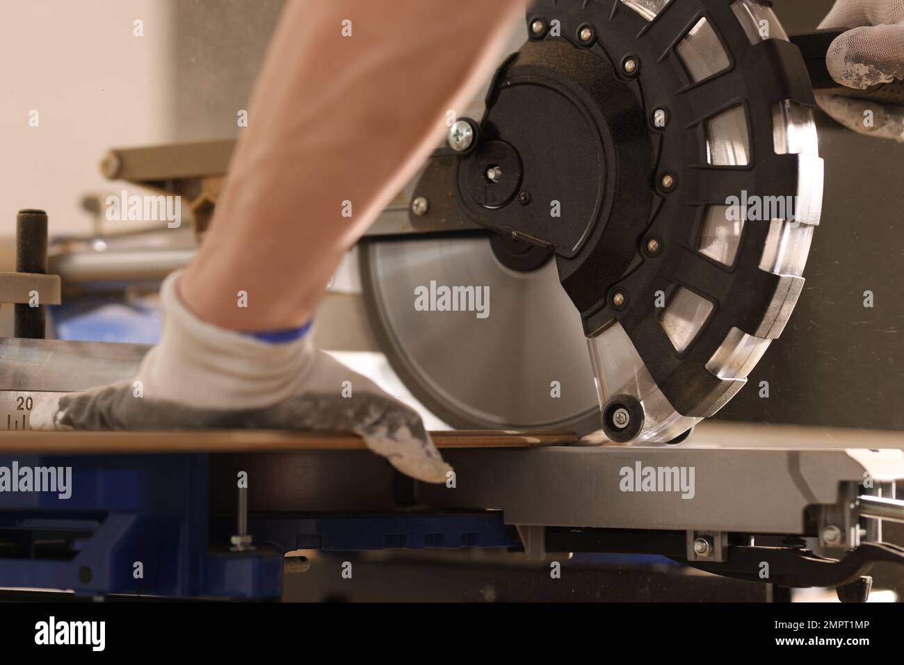 Construction worker sawing wooden board with power end saw closeup ...