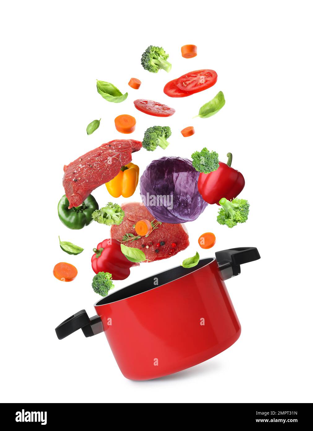 Many different ingredients falling into pot on white background ...