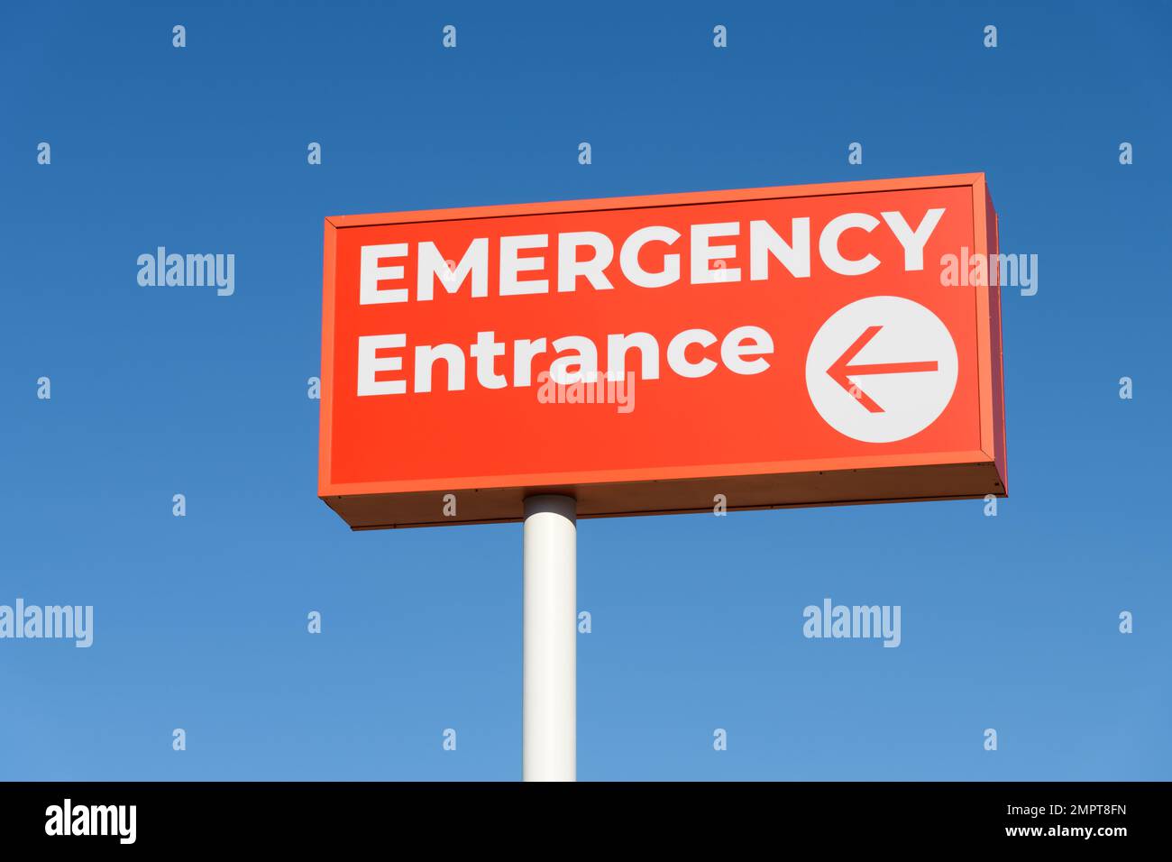 Emergency entrance sign in red and white isolated against blue sky with ...