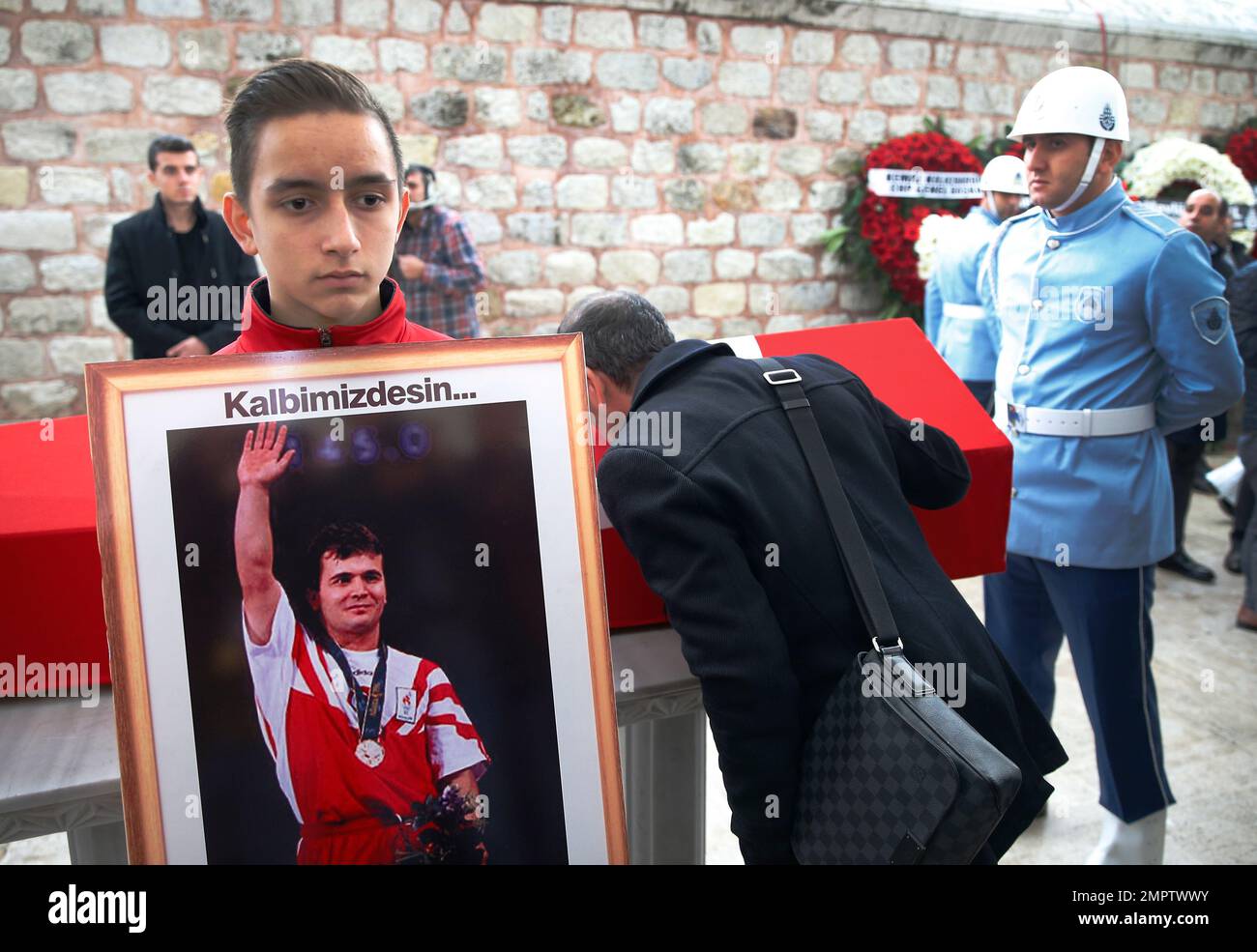 Flanked by a youth holding a photograph of Turkish weightlifter Naim ...