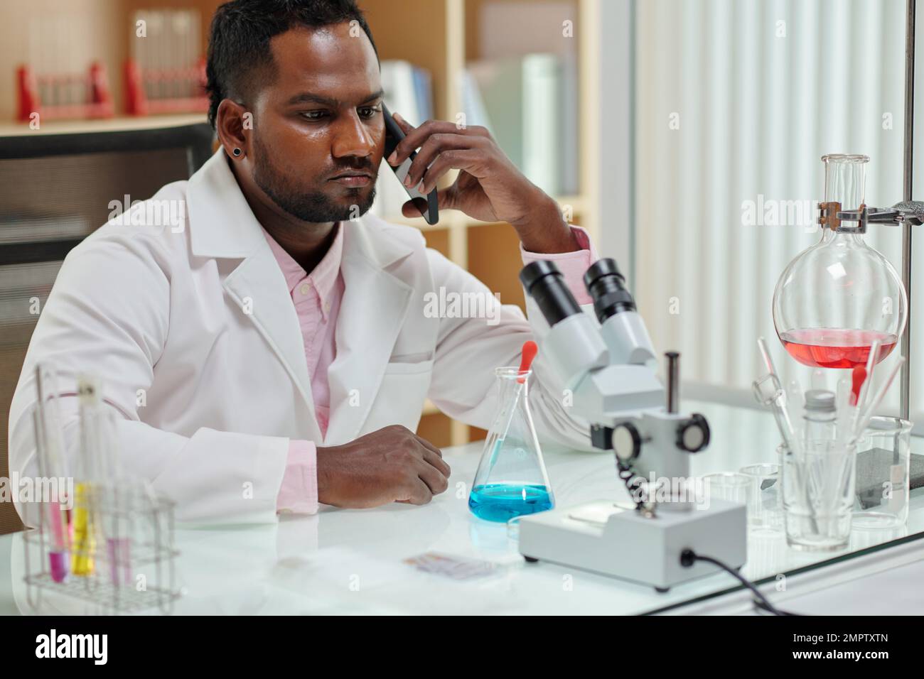 Medical laboratory worker talking on phone with patient of coworker ...