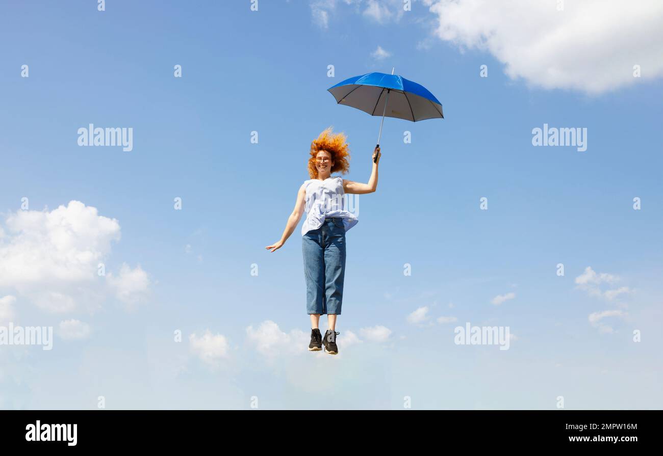 Young woman hopping with an umbrella Stock Photo - Alamy