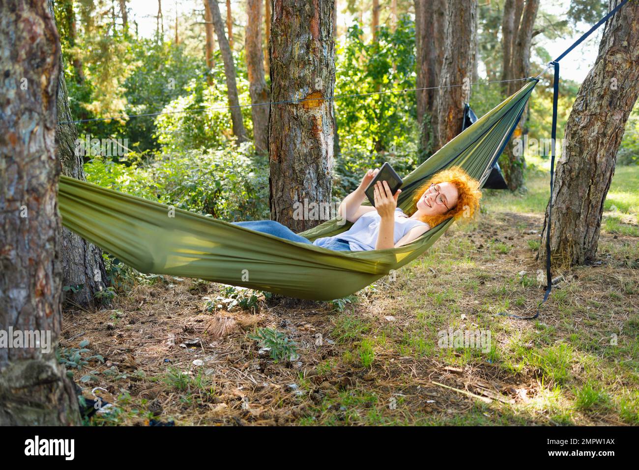 Young woman camping and reading in a hammock Stock Photo - Alamy
