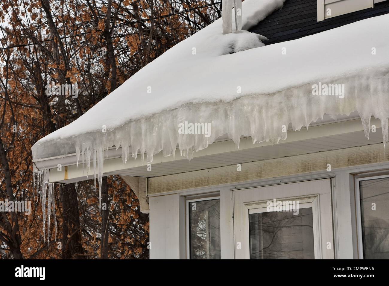 Melting snow on roof causing ice dam in gutter with icicles forming ...