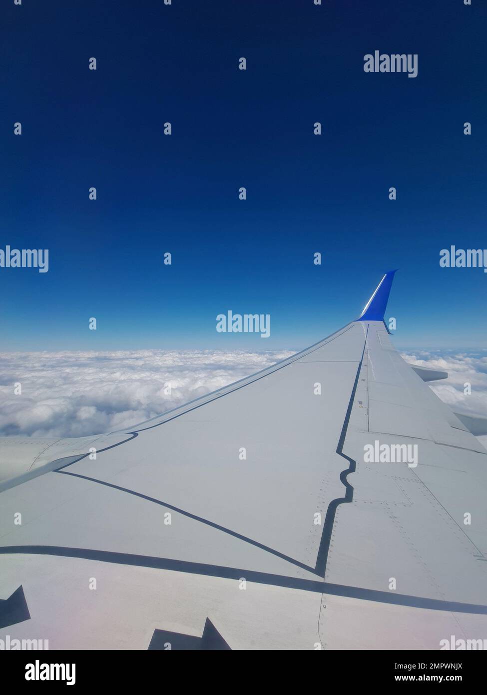 Travel on airplane theme. Jet wing over clouds in blue sky background ...