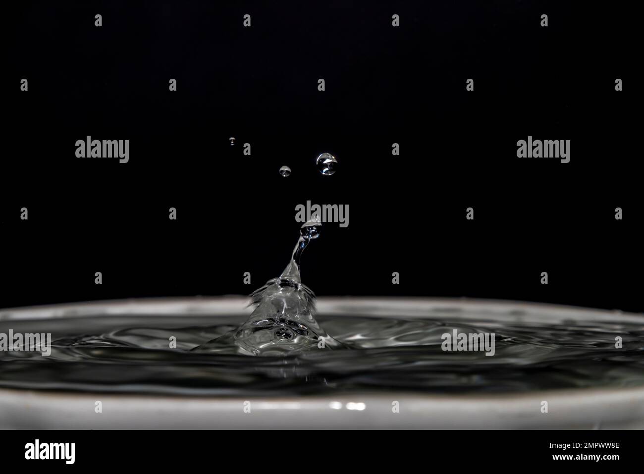 Clean water drops into clean water in white cup with black dark ...