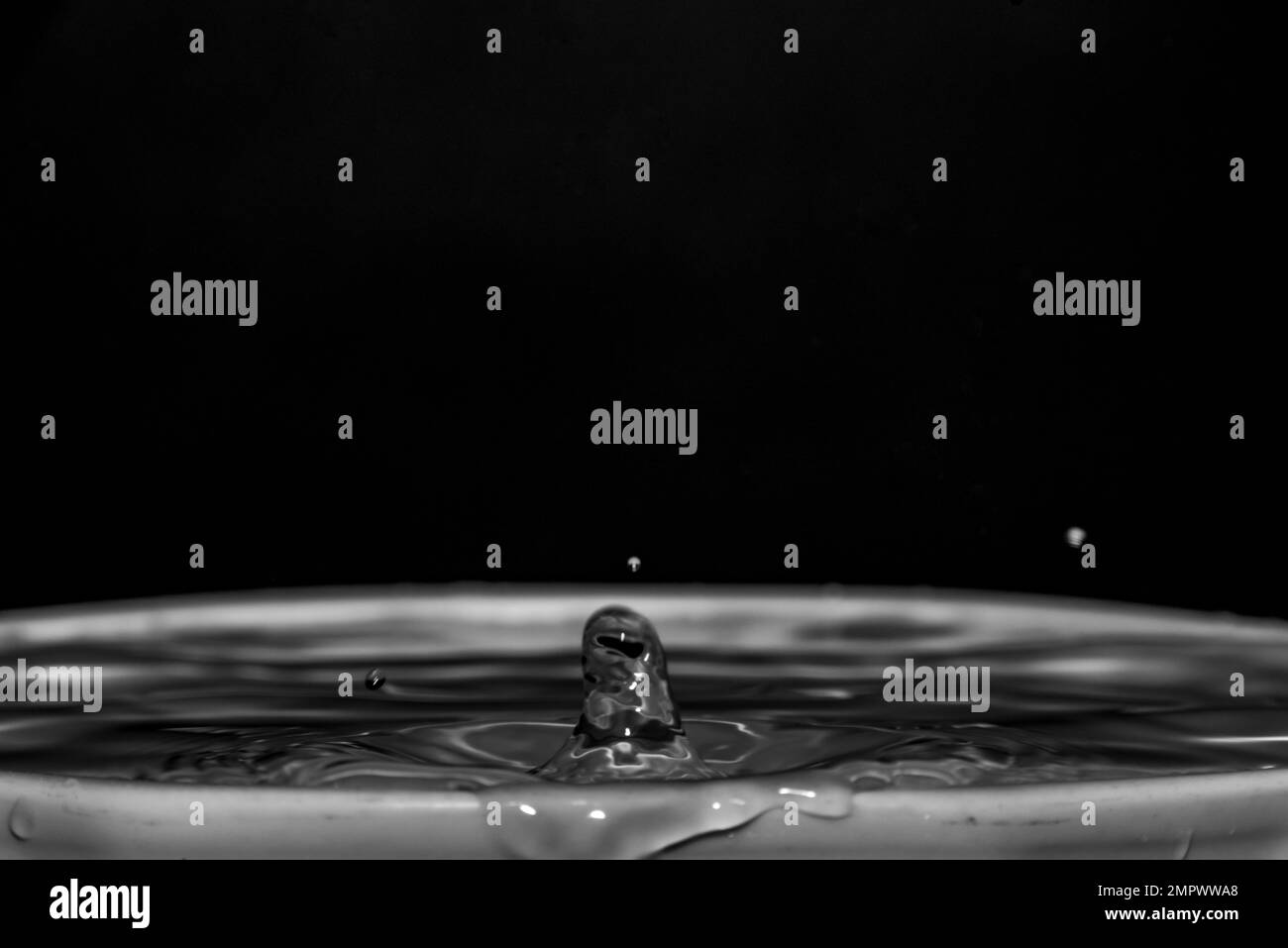 Clean water drops into clean water in white cup with black dark ...