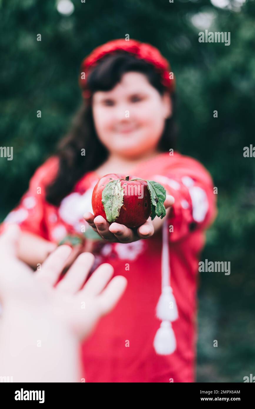 A girl in red gives a red apple to another girl. Presented apple Stock ...