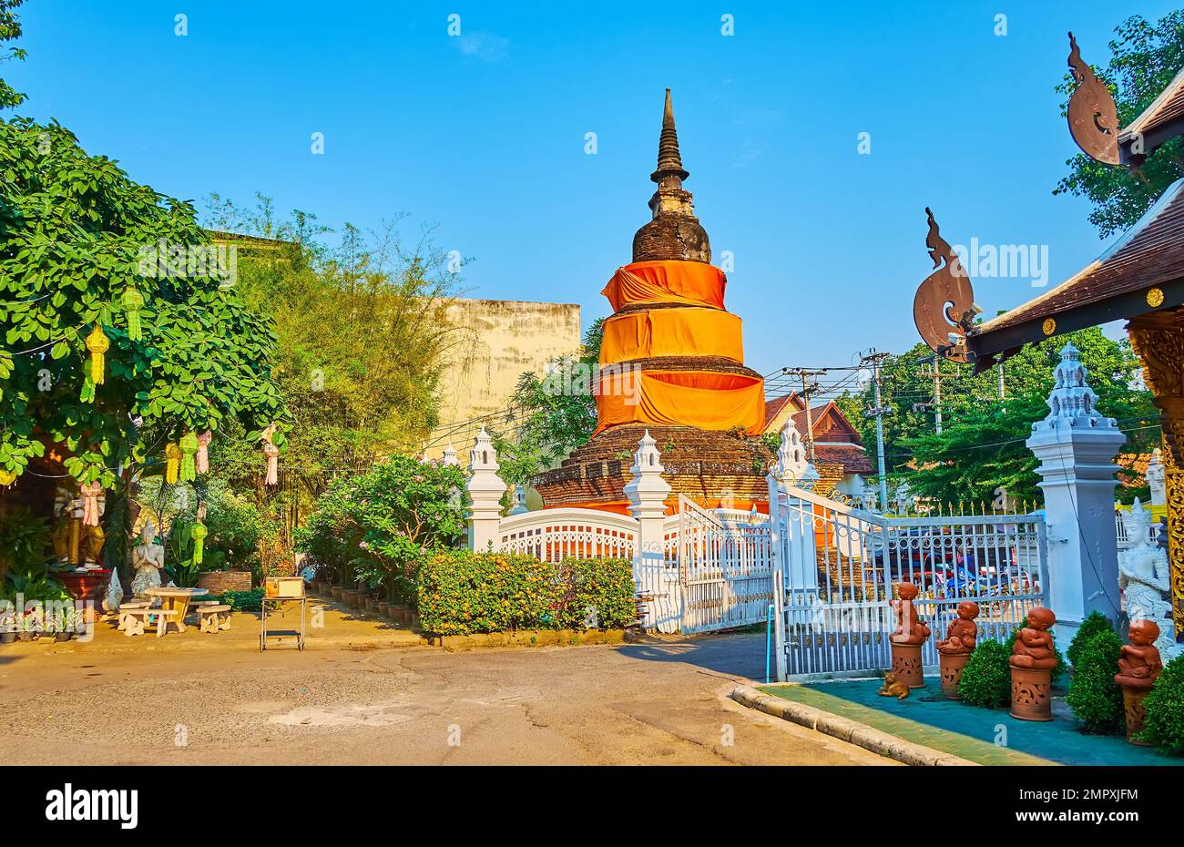 The green garden of Wat Inthakhin Sadue Muang with ancient brick Chedi ...