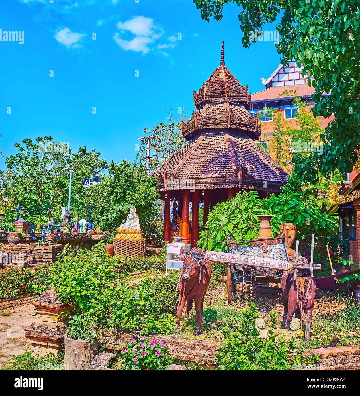 The flowering garden of Wat Lok Moli with small shrines, wooden ...