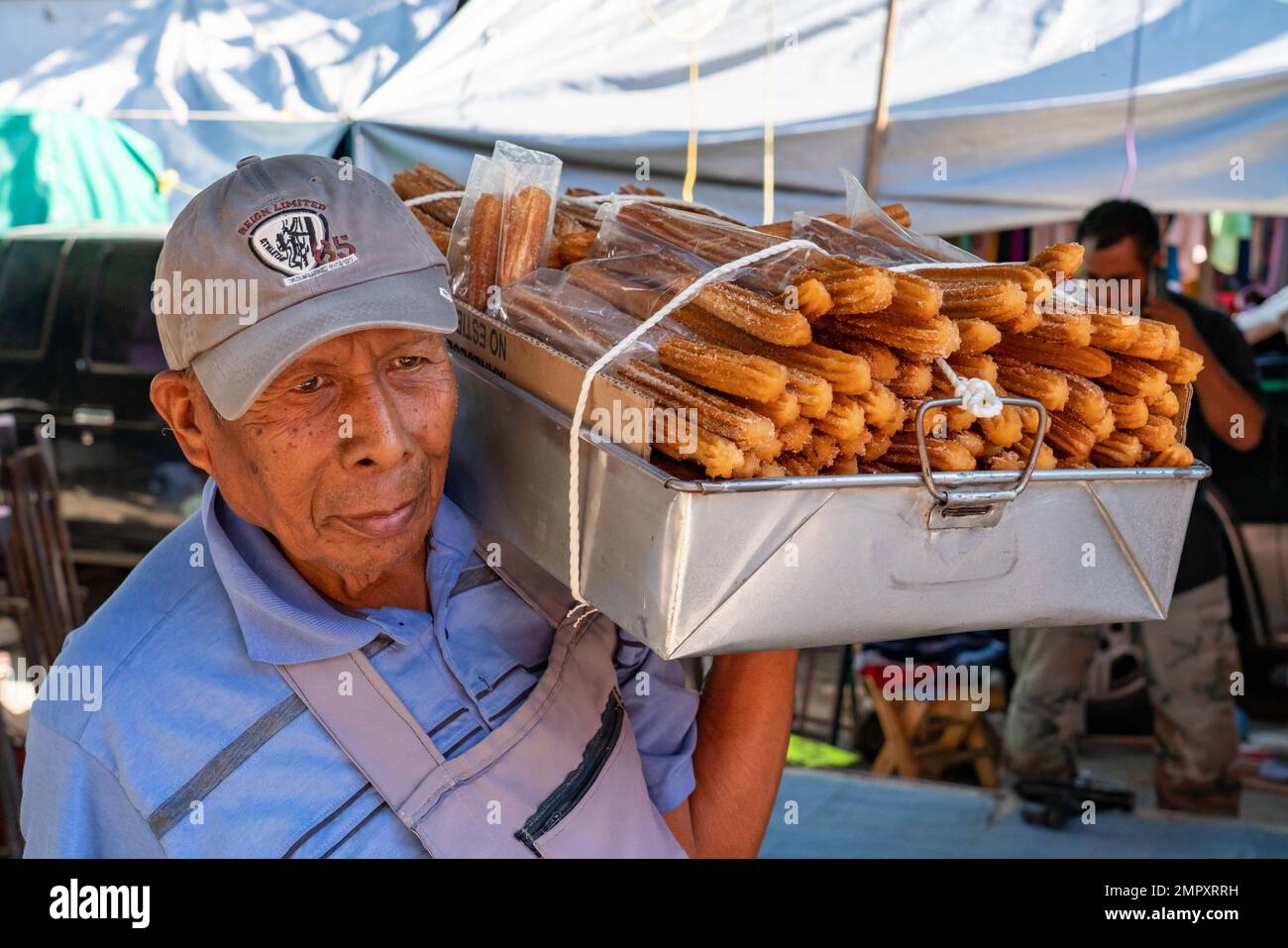 A vendor carries a tray of churros for sale in the market in Ocotlan de ...