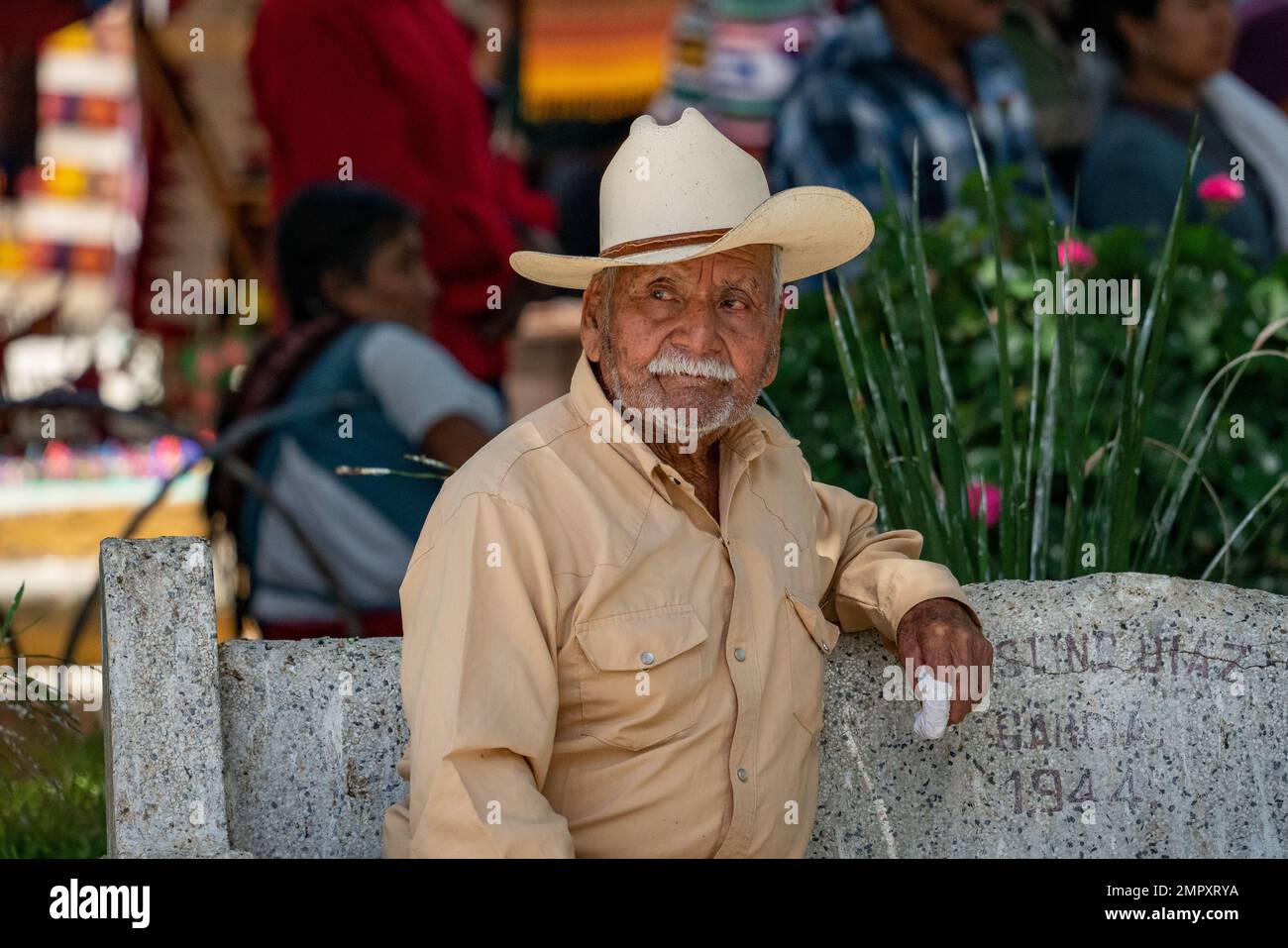An older man sitting on a bench in the market in Ocotlan de Morelos in ...