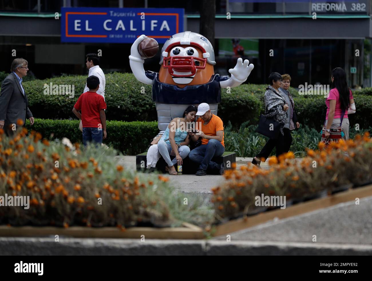 People pose for a picture in front of a giant figure of Mr. Potato Head ...