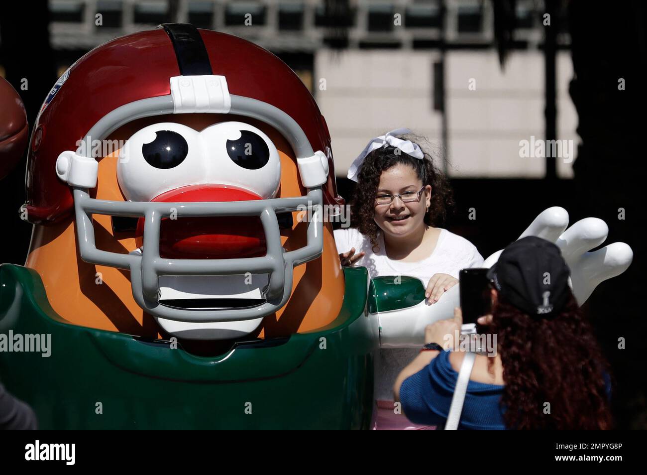 A girl poses for a picture with a giant figure of Mr. Potato Head ...