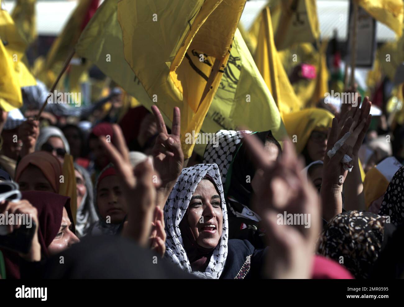 Palestinian women wave the Yellow Fatah movement flags during a rally ...