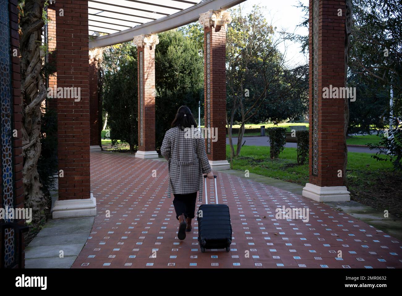 girl walking turning her back carrying a suitcase to go on vacation ...