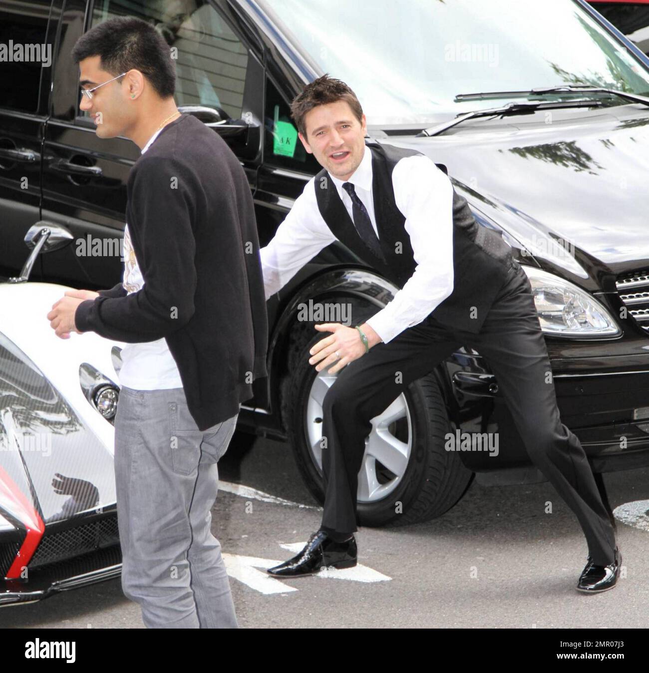 Tom Chambers jokingly poses by a super swank Pagani Zonda sports car ...