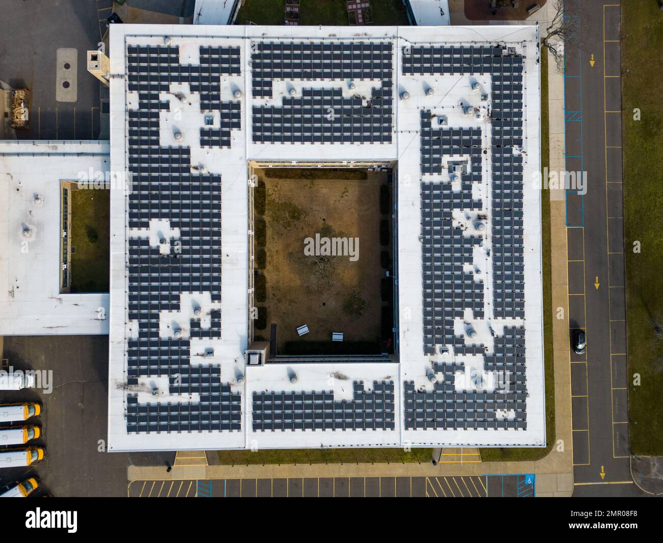 an aerial shot of a square school building with many solar panels on ...