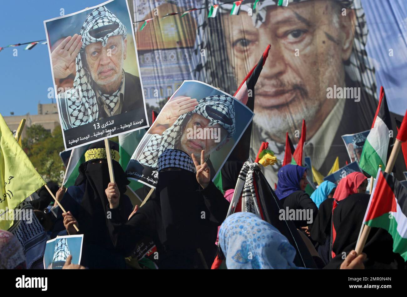 Palestinians wave flags and carry pictures of the late Palestinian ...