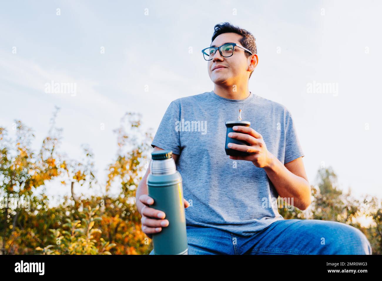 Hispanic young man drinking mate and relaxing, in a rural space, on top ...