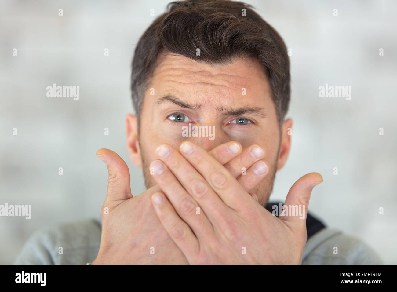 closeup portrait of man with hand over his mouth Stock Photo - Alamy
