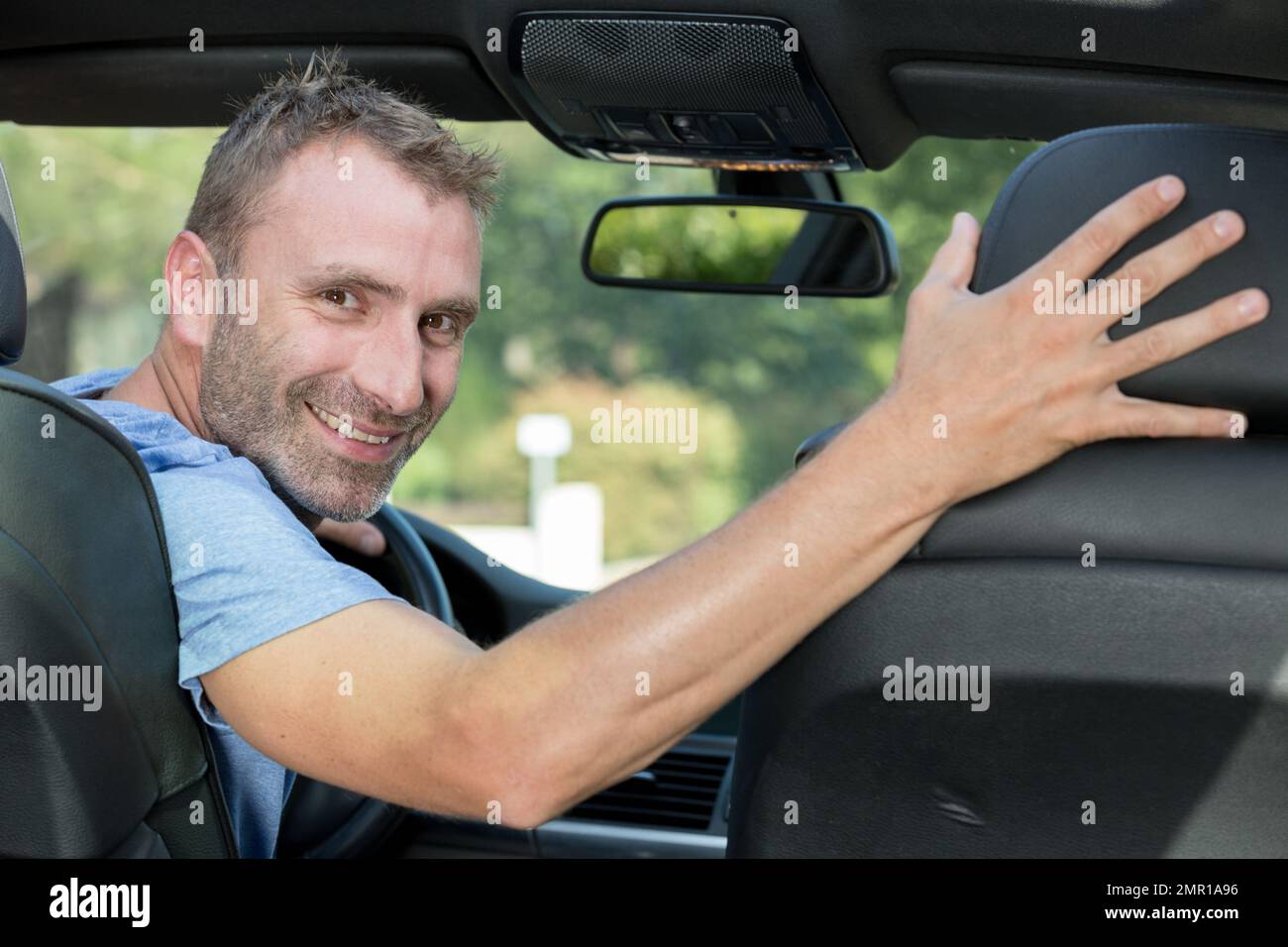 cheerful professional man driving a car in reverse Stock Photo - Alamy