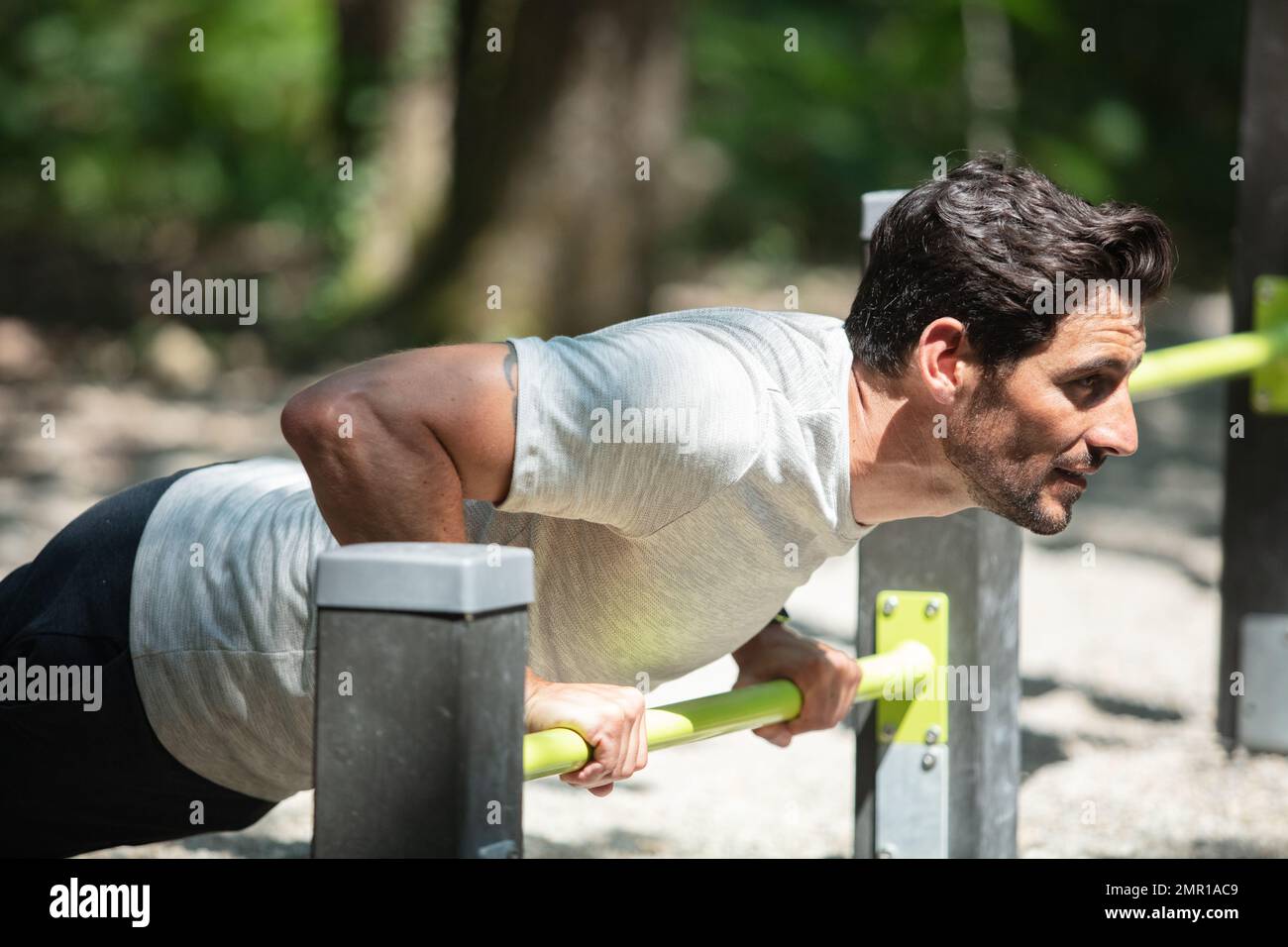 fit man workout out arms on dips horizontal bars Stock Photo - Alamy
