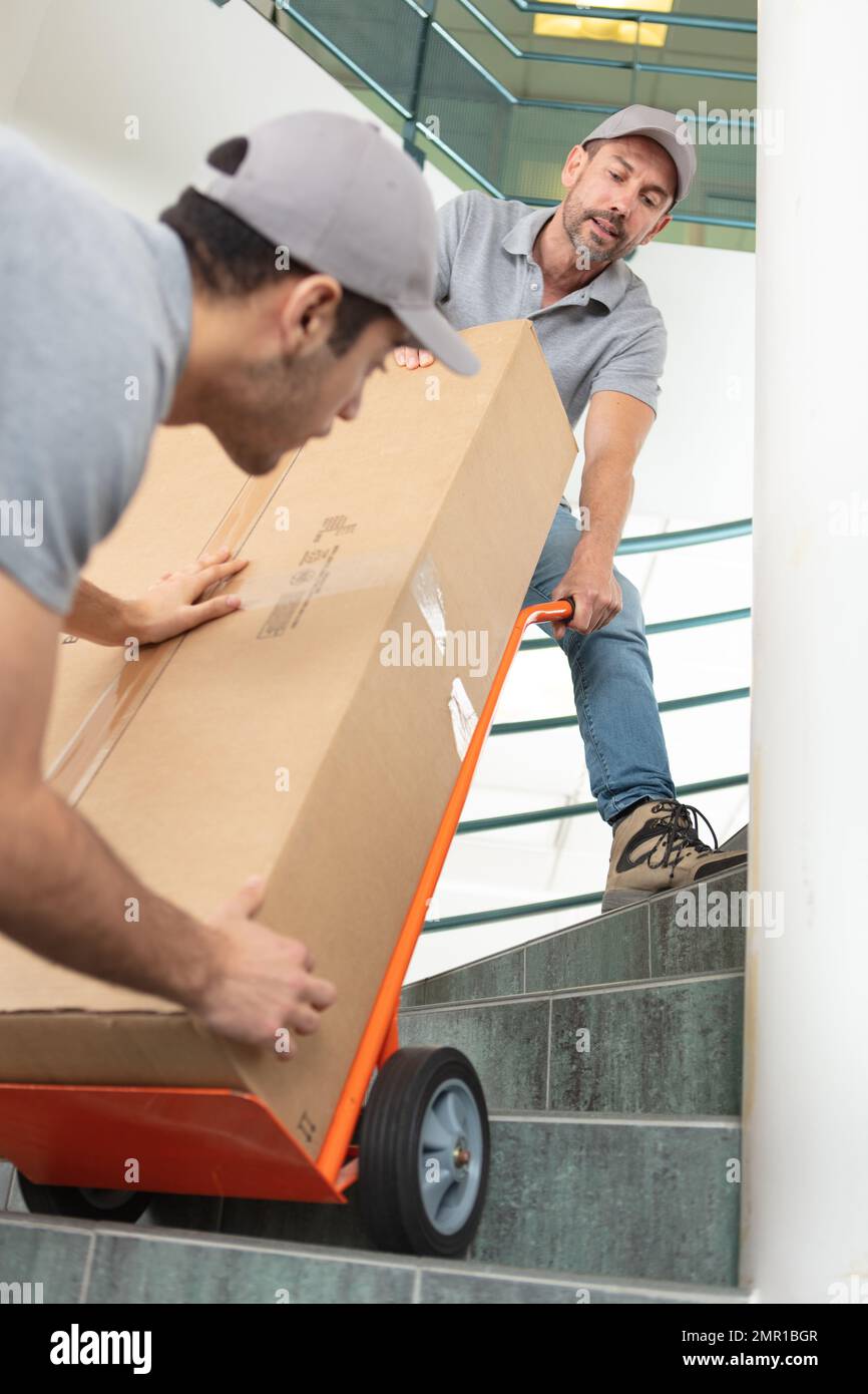 two male movers lifting box on staircase Stock Photo - Alamy