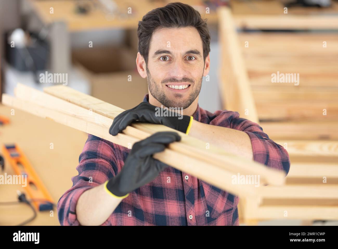 handsome carpenter holding wood planks in shoulder Stock Photo - Alamy