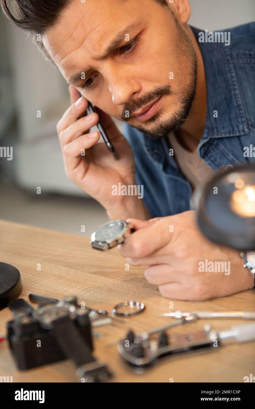 man on the phone while fixing a watch Stock Photo - Alamy