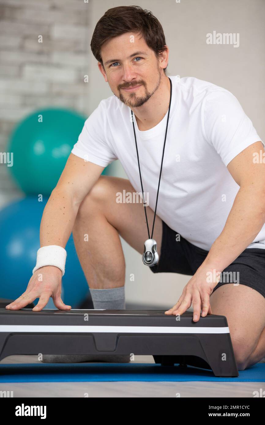 personal trainer crouching by step accessory Stock Photo - Alamy