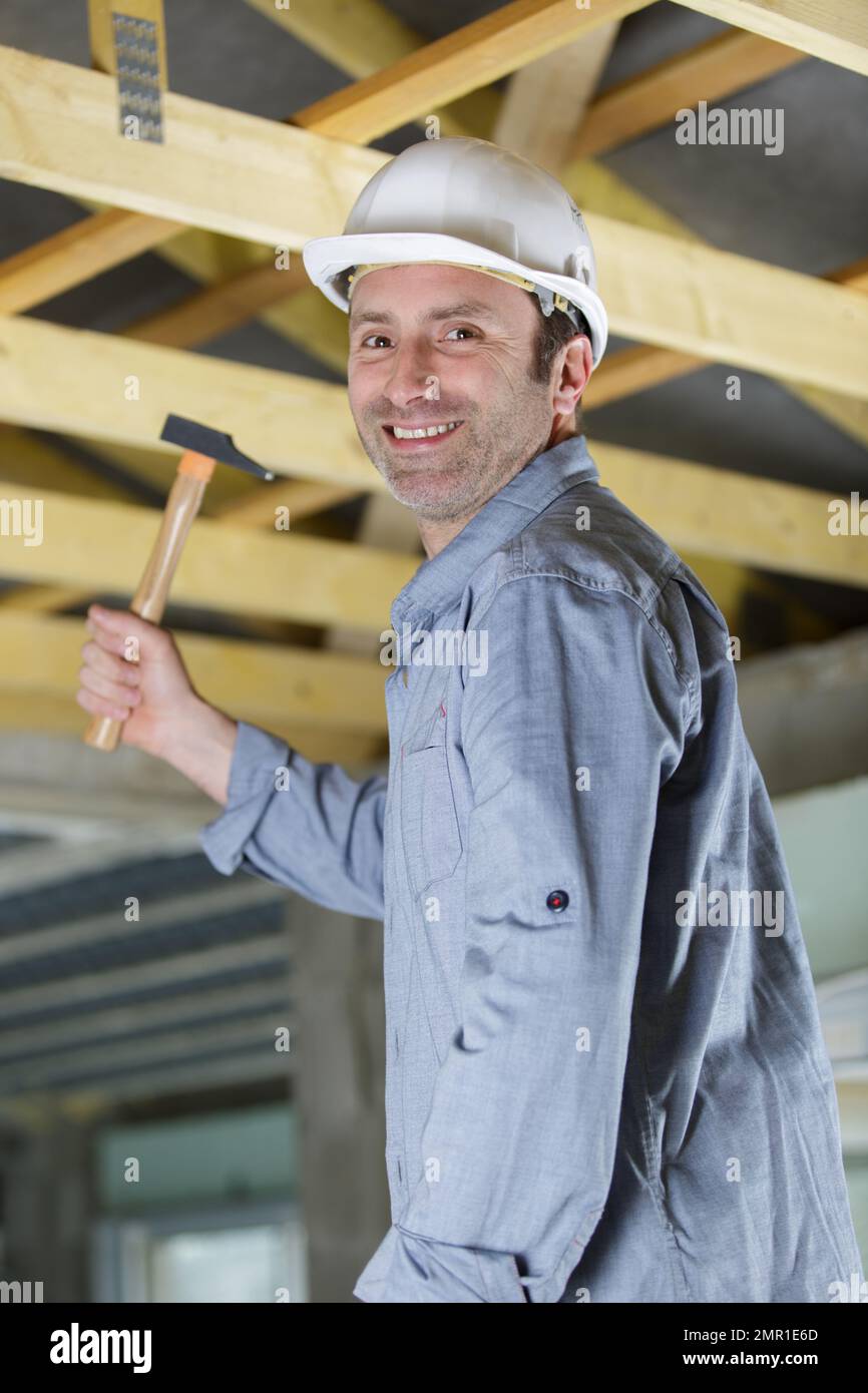 happy man builder hammer wood structure indoors Stock Photo - Alamy