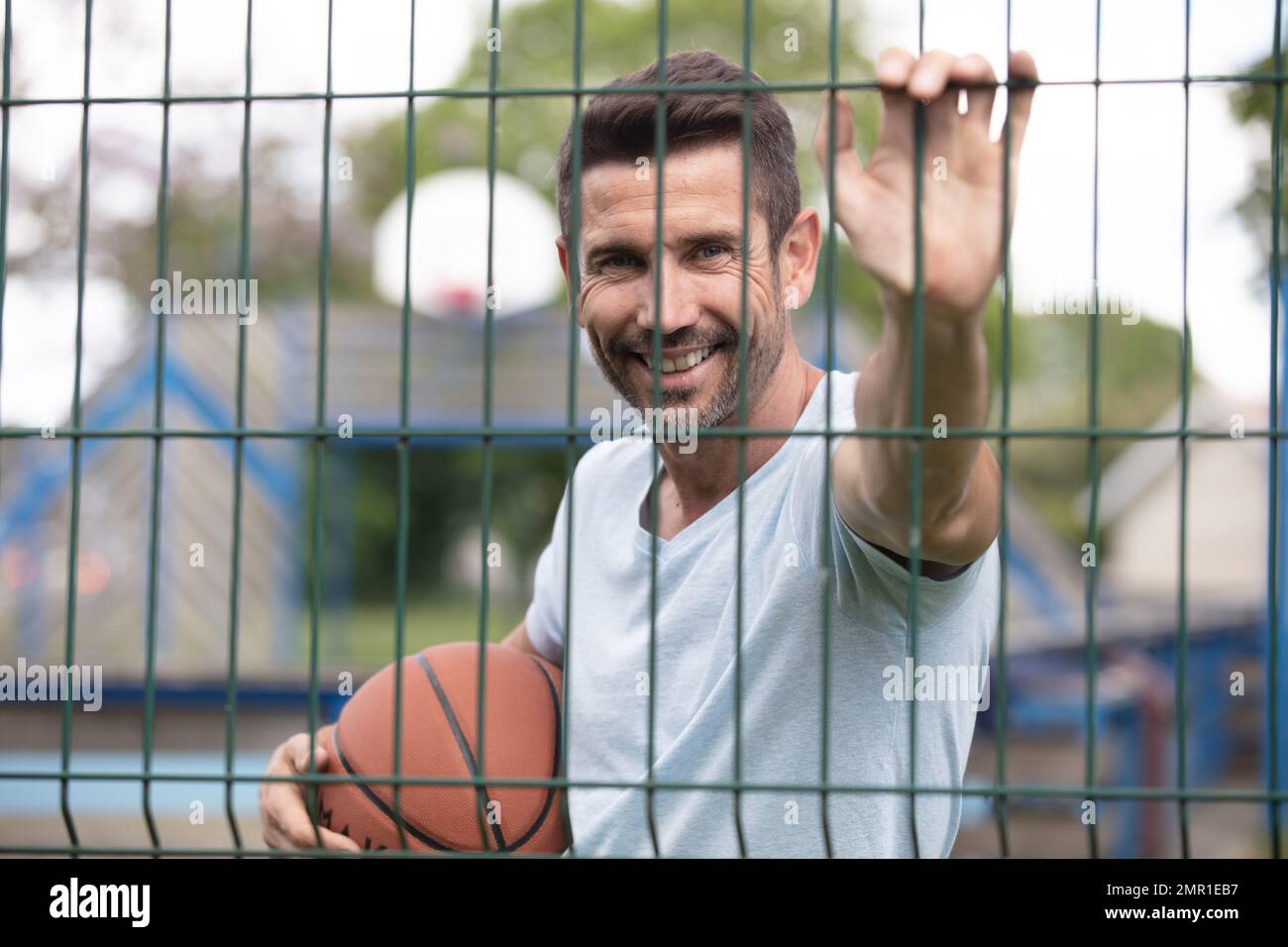 portrait of exhausted male basketball player leaning on fence Stock ...