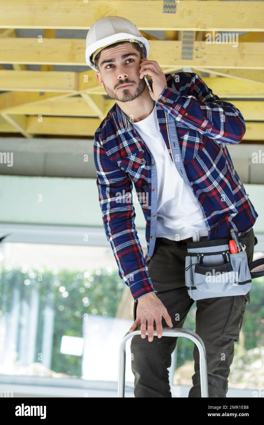 builder on the phone on a ladder Stock Photo - Alamy