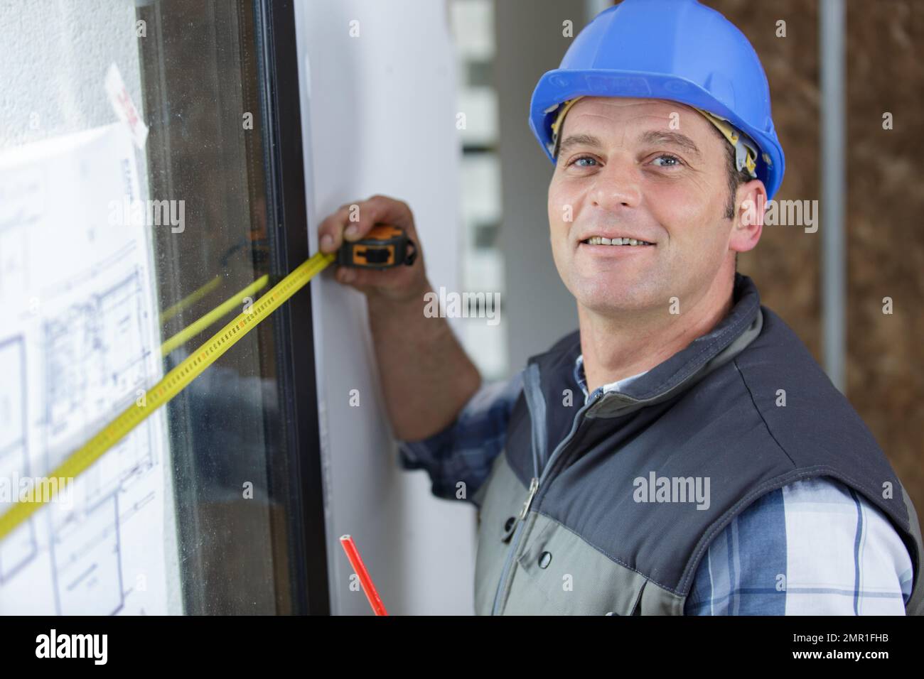 builder is measuring window using measure tape at construction site ...