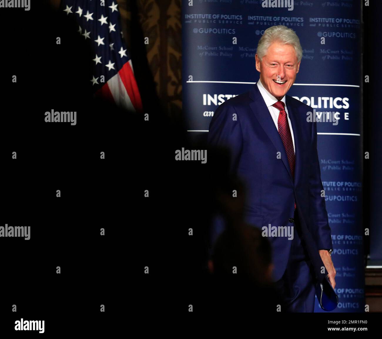 Former President Bill Clinton smiles as he arrives at a symposium in ...