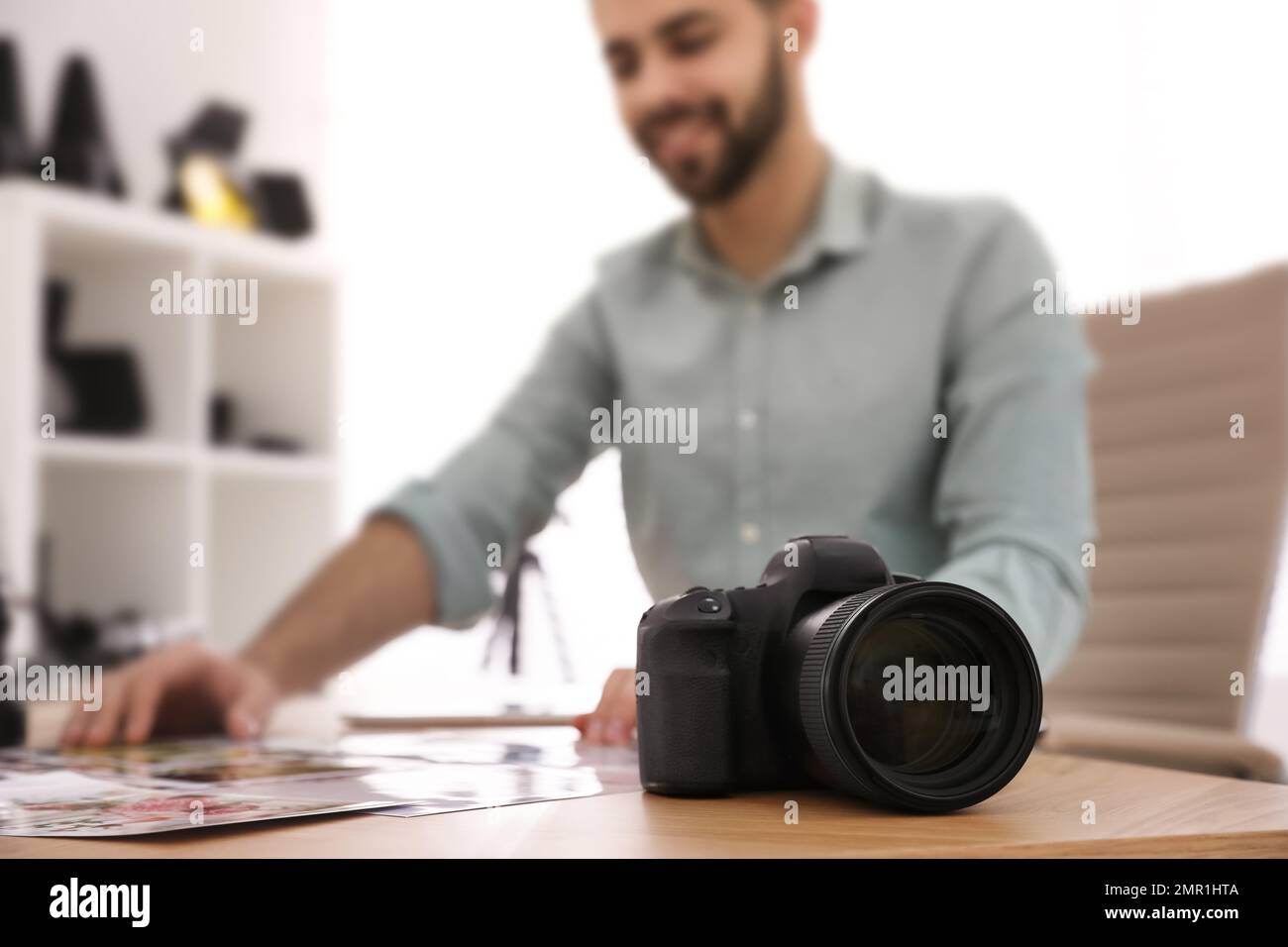 Professional photographer working at table in office, focus on camera ...